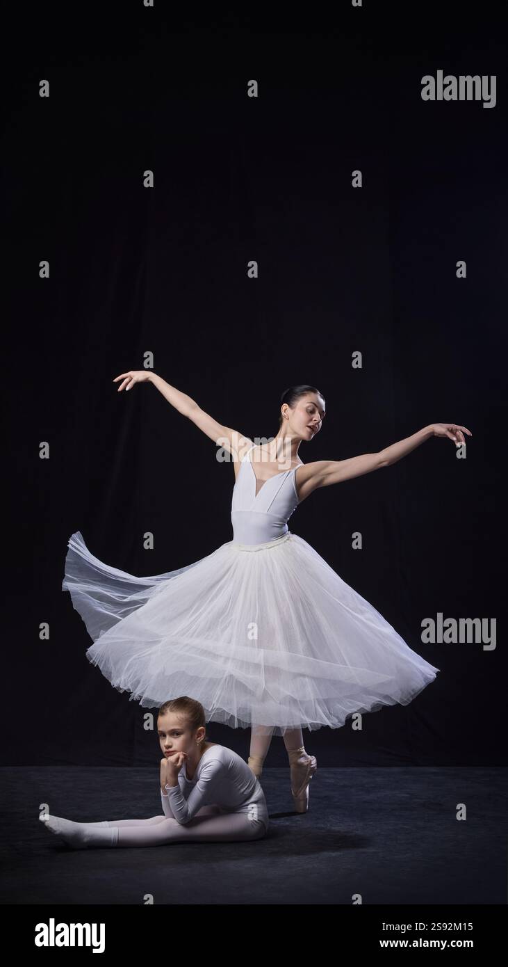 Adult ballerina spinning elegantly in tutu while young ballerina poses ...