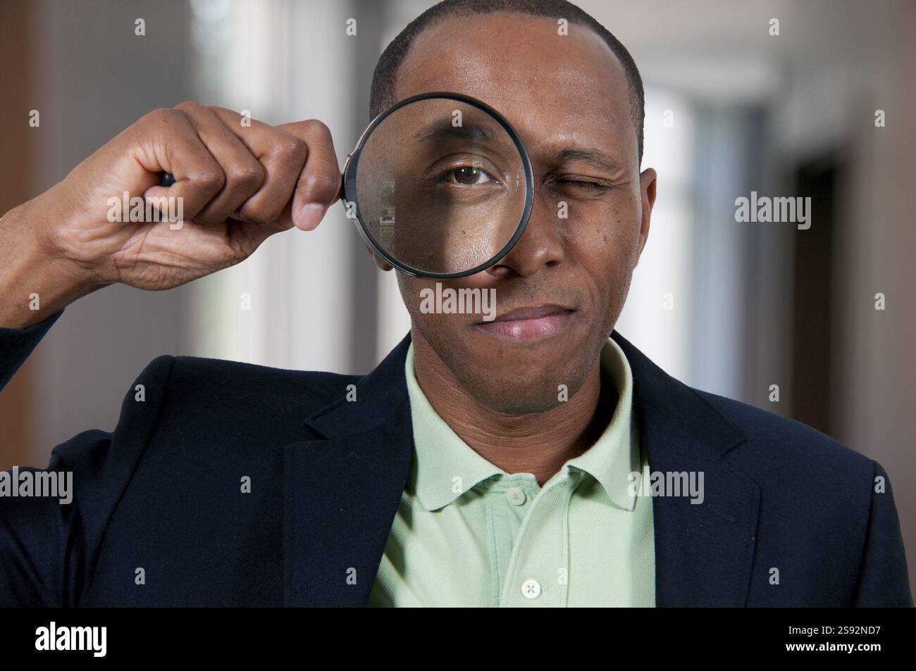 Handsome African American man looking through a large magnifying glass ...
