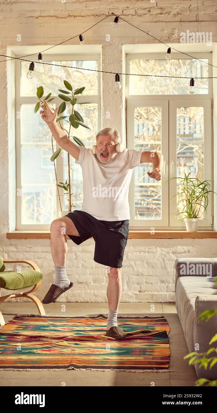 Emotional and energetic elderly man in home wear listening to music in ...