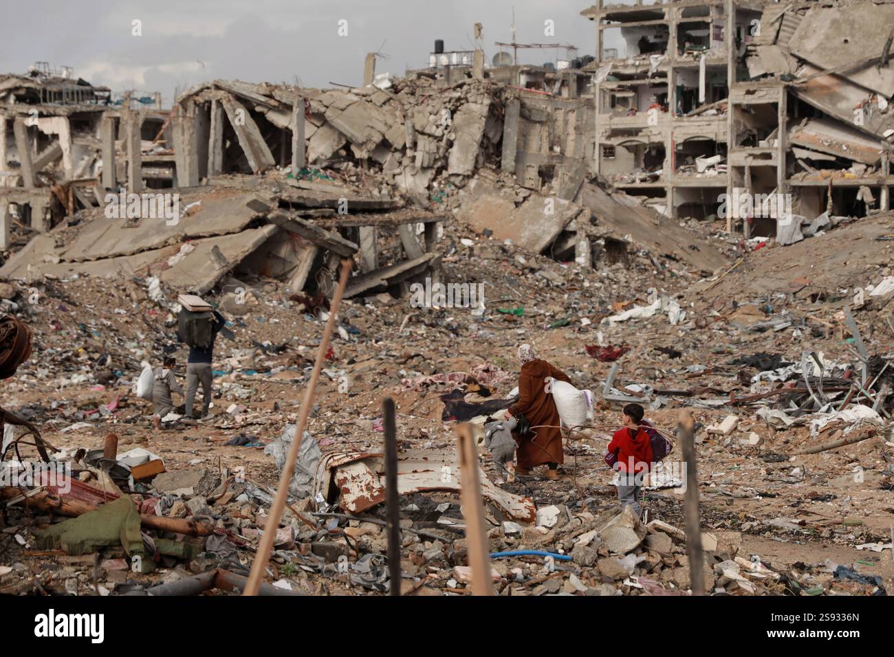 Palestinians walk on the rubble of destroyed houses, after the ...
