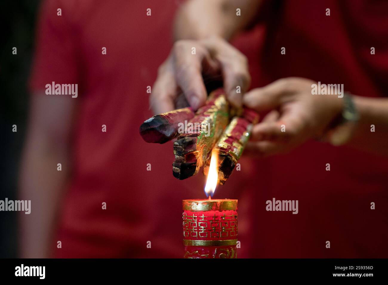 Hand holding joss sticks and candle as prayer and offering to the Gods ...