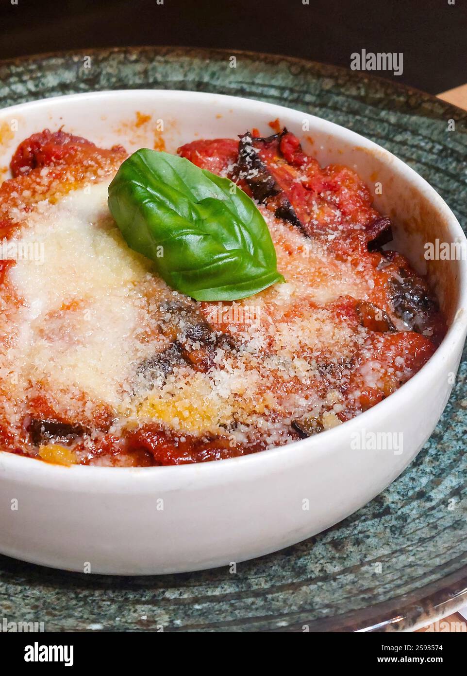 Close up of a delicious parmigiana with basil leaf and grated parmesan ...
