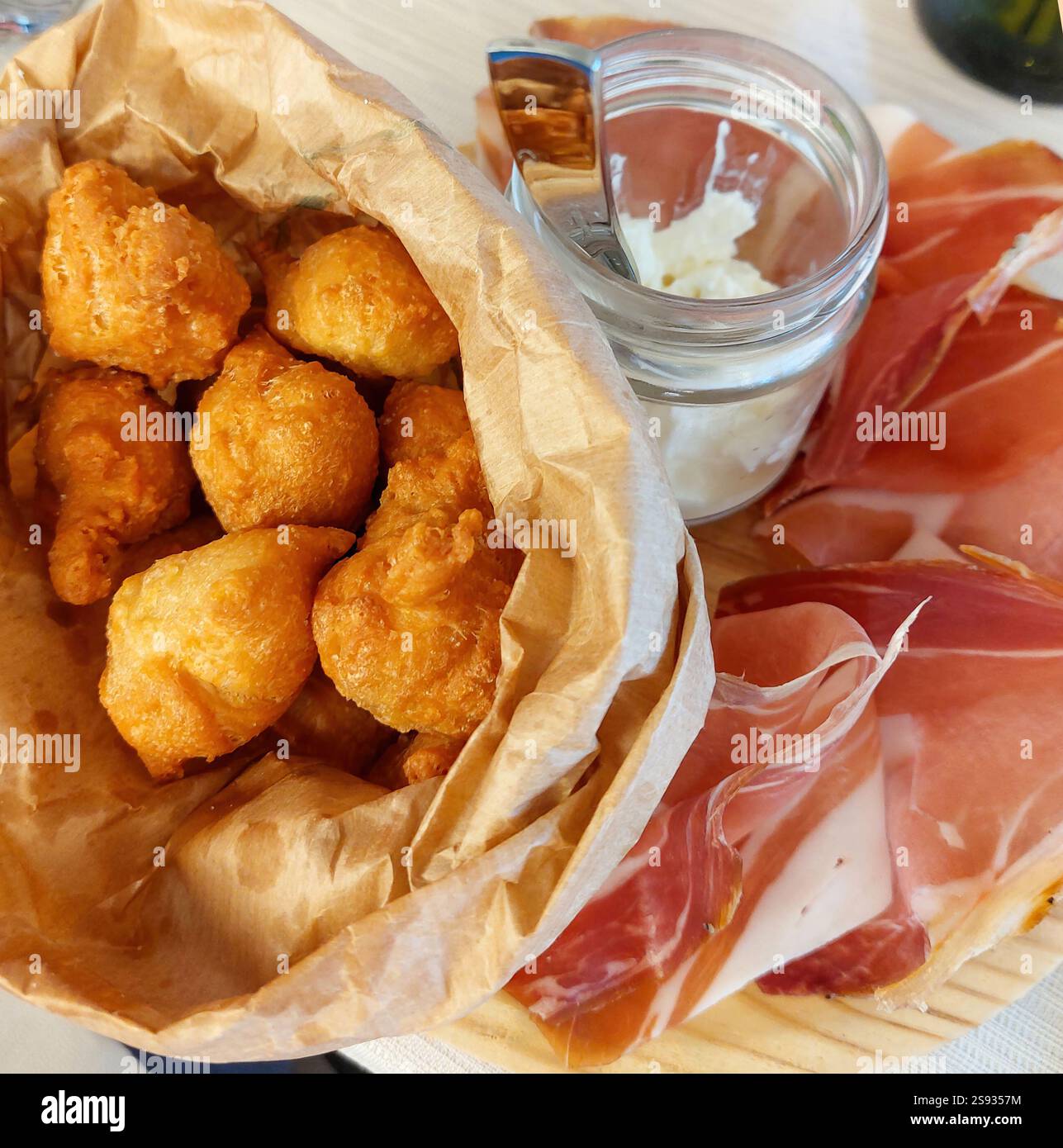 Delicious fried dumplings inside a paper bag served with cured speck ...