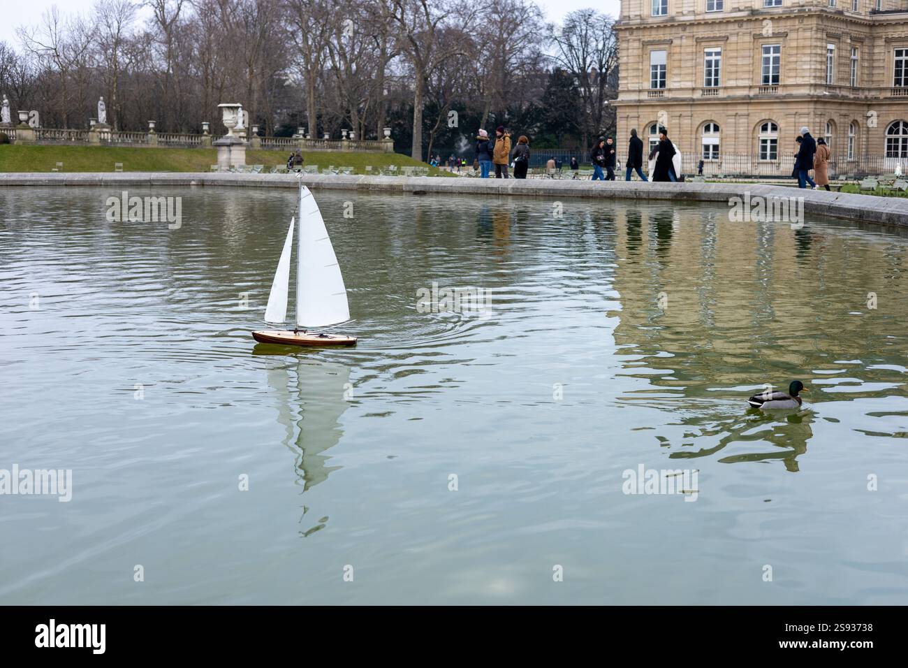 Small remote-controlled boat sailing on a calm lake in the afternoon ...