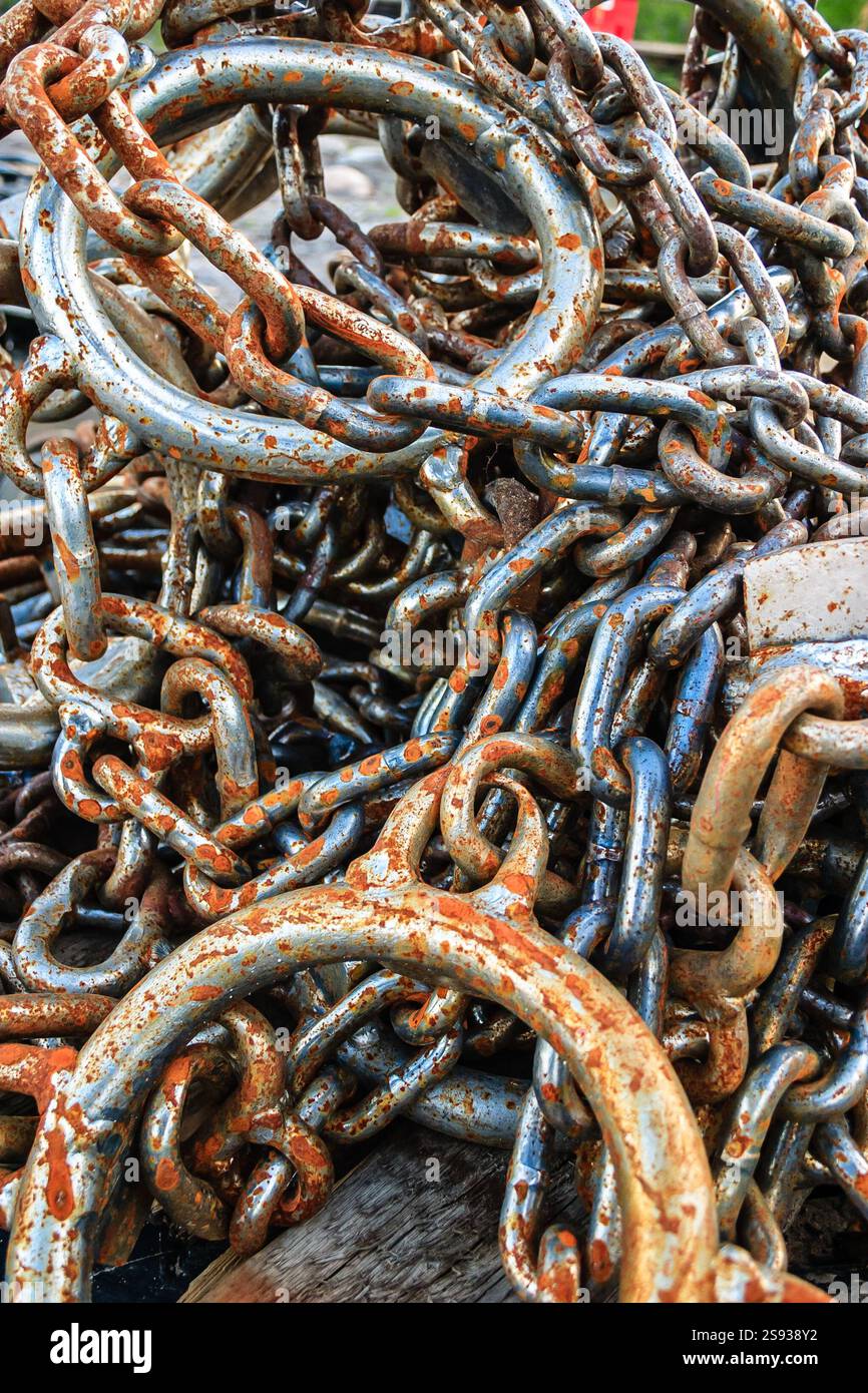 A pile of rusty chains with a few of them having a silver ring. The ...