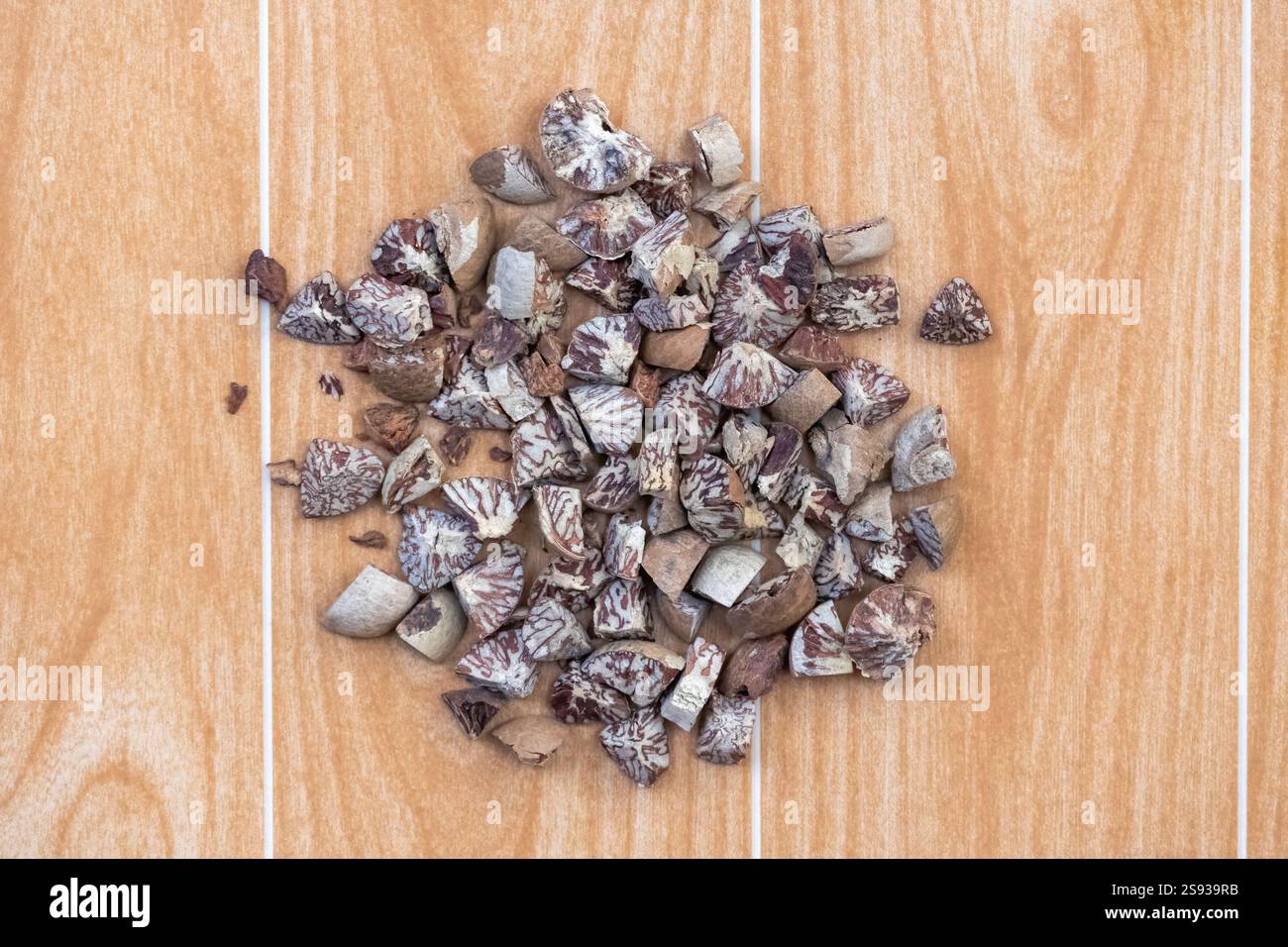 Betel nut fruit cut into small pieces on a wooden background. This ...
