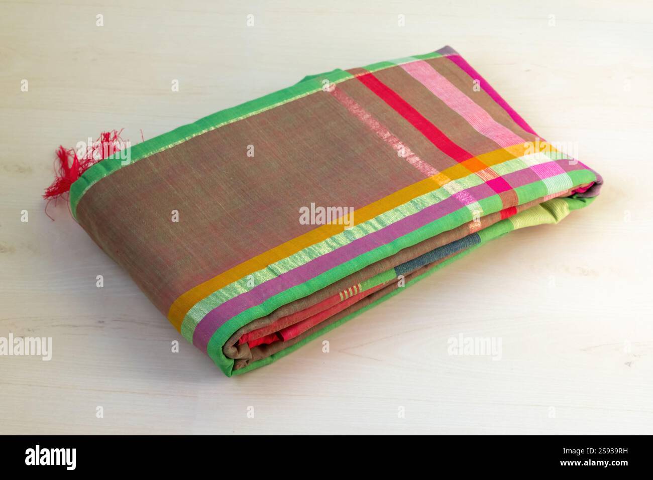 A folded green cotton saree rests on a wooden backdrop. Sarees are a ...