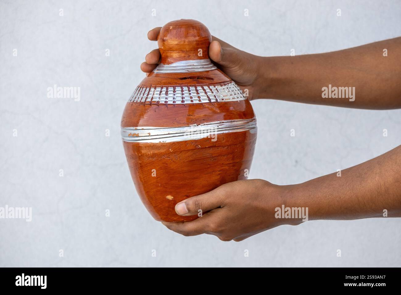 A female hand displays a clay bank for saving money against a white ...