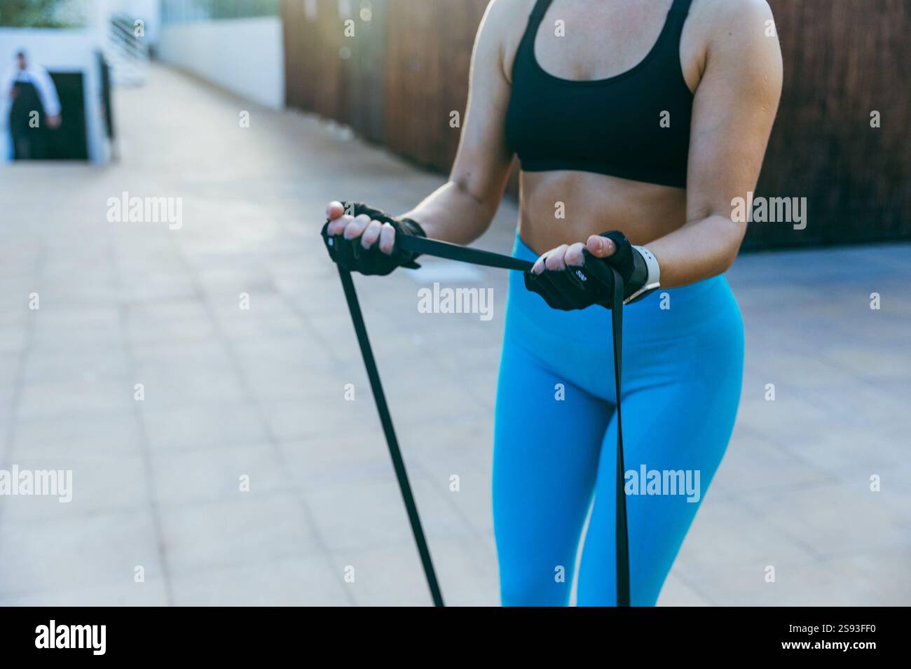 A woman is trains with a resistance band while standing outside ...