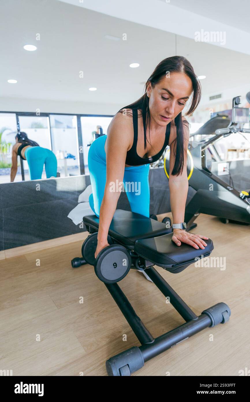 A woman is lifting weights on a bench. The bench has a number 9 on it ...