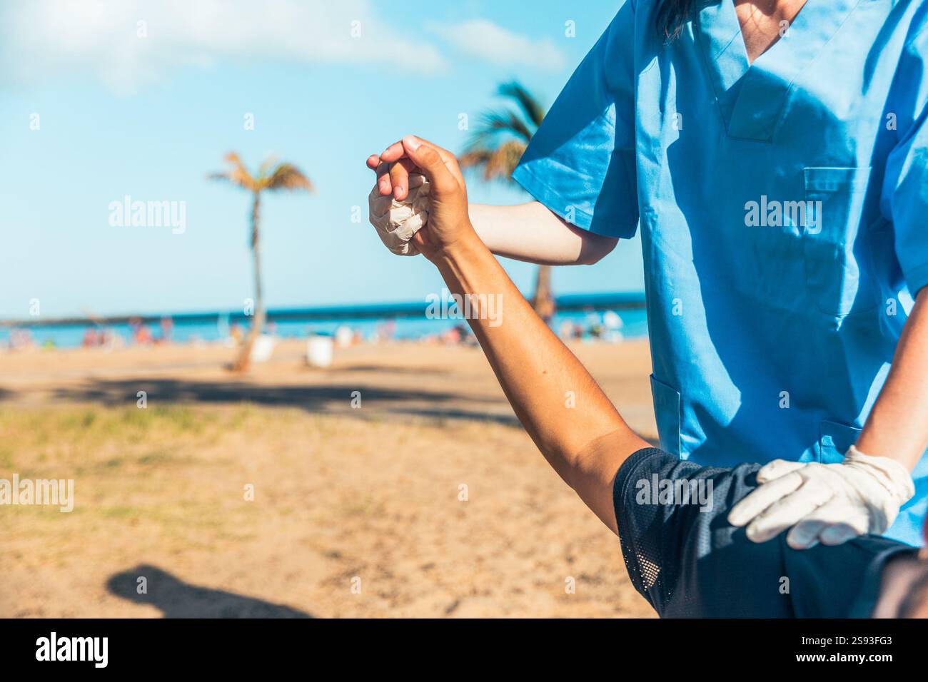 A doctor is helping a patient with his arm injury at the beach Stock ...