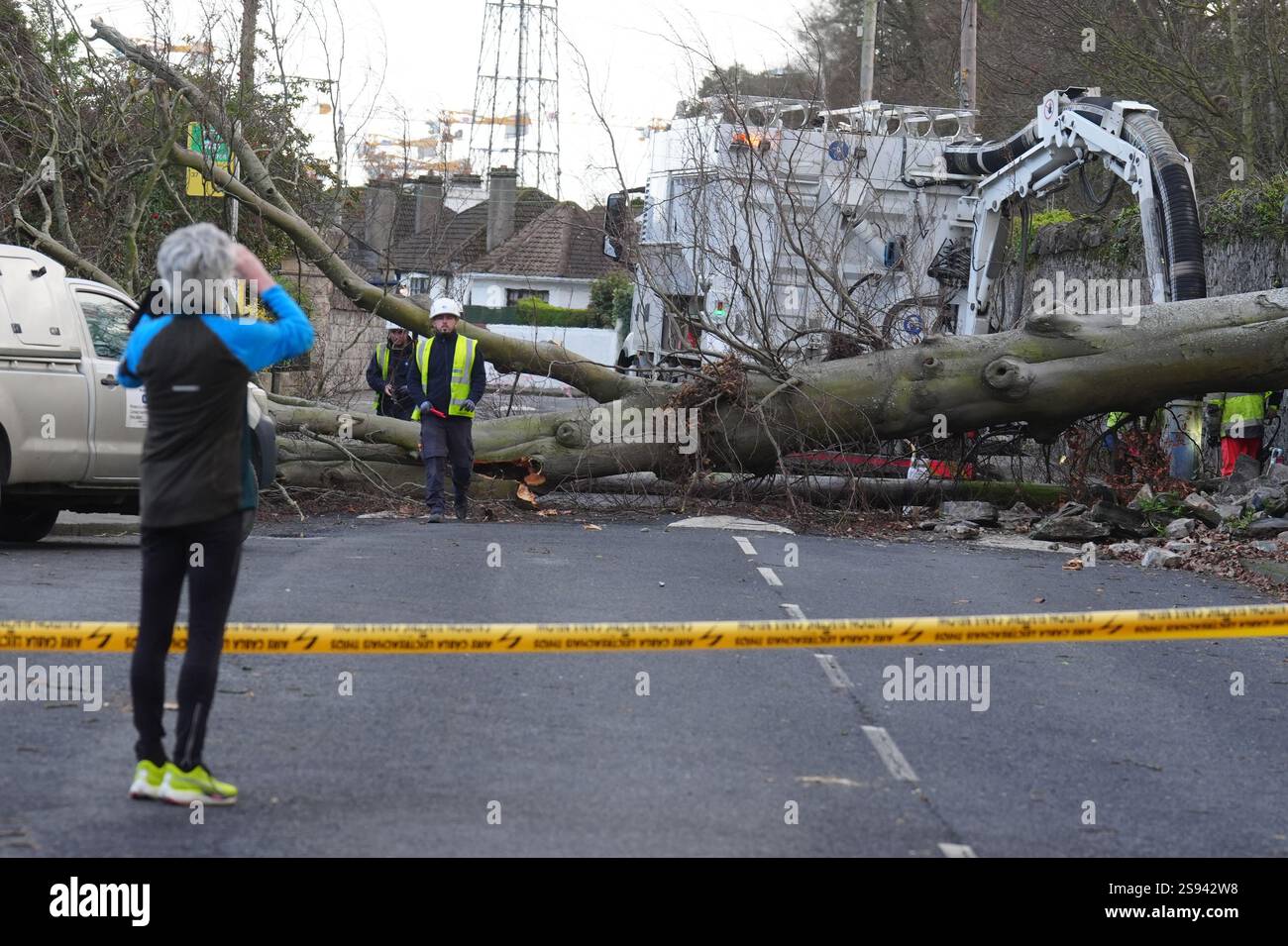 A woman photographs a fallen tree which crashed through the wall of ...