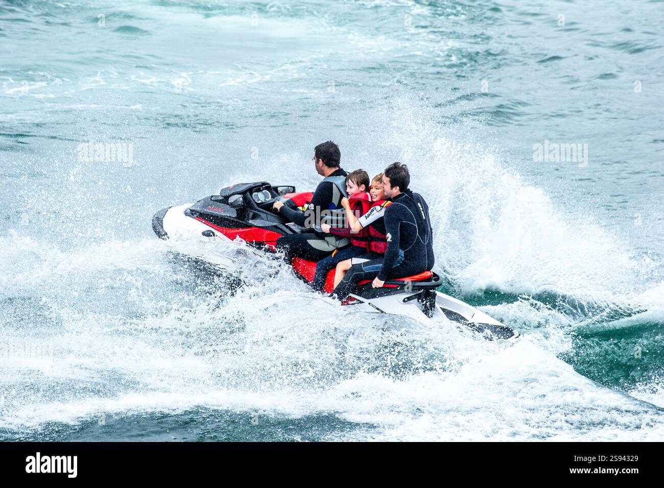 Jet ski creating spray with two adults & two children offshore ...
