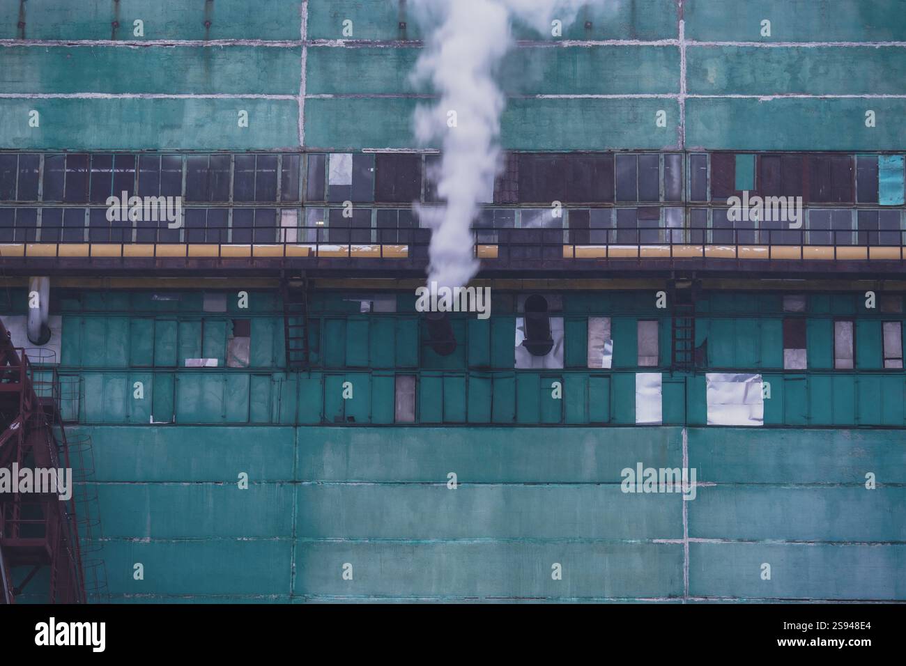 An industrial building under renovation, covered with green scaffolding ...