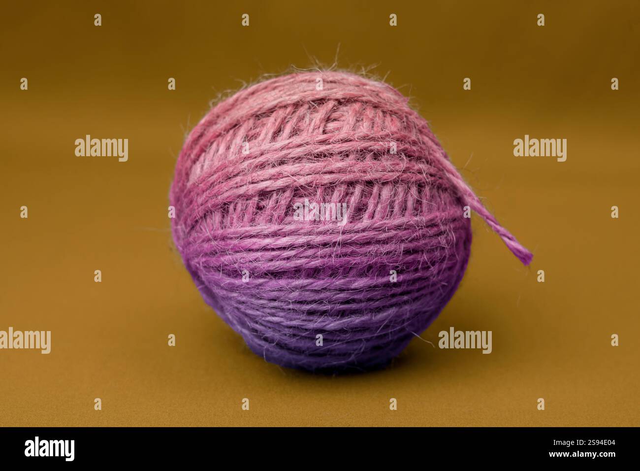 A close-up of a ball of purple gradient yarn placed on an olive green ...