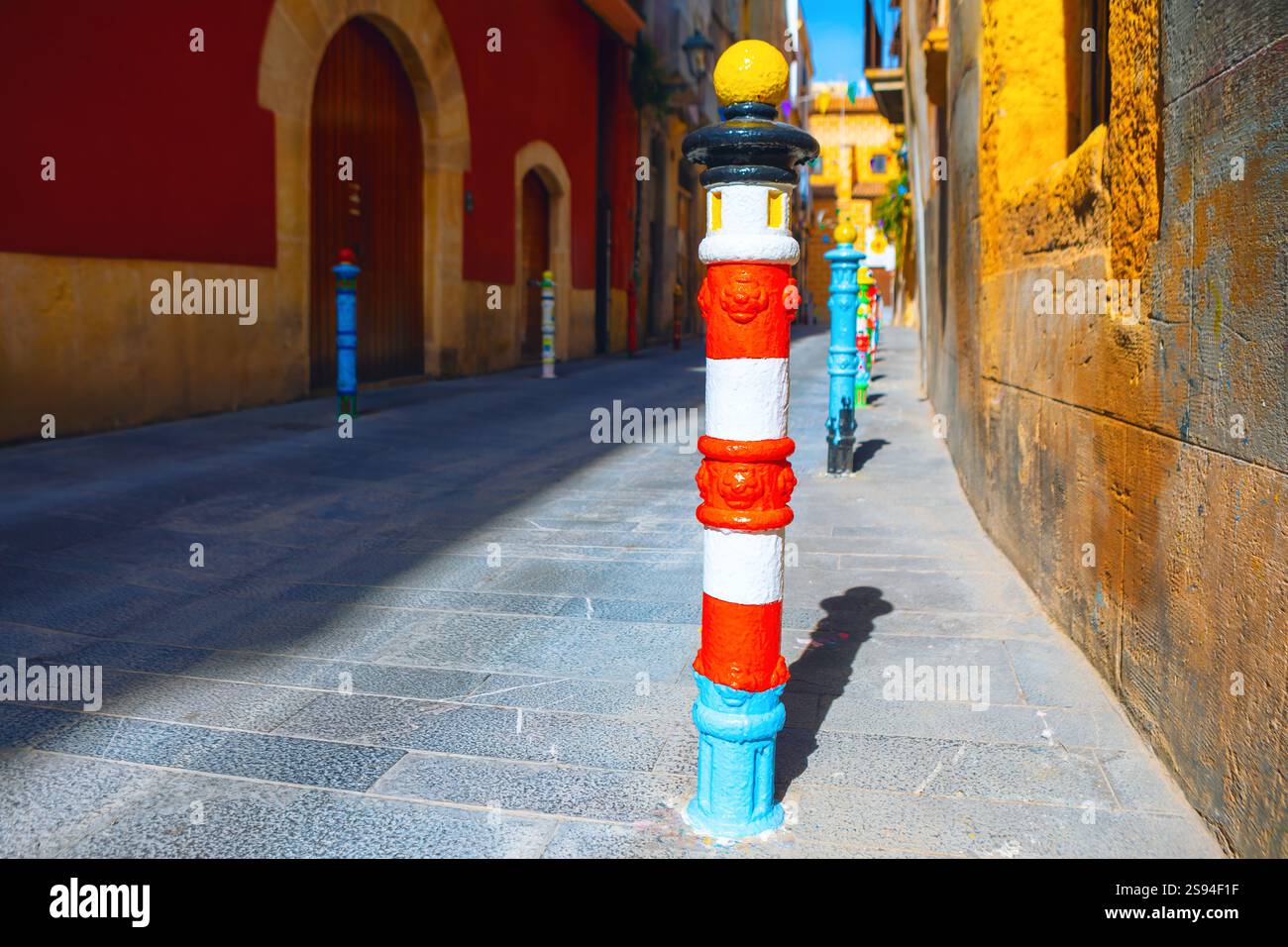Colorful painted bollard stands along old town street Stock Photo - Alamy
