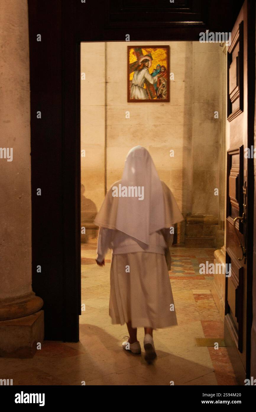 Nun in a white habit walks into the chapel at the famous Bascilica in ...