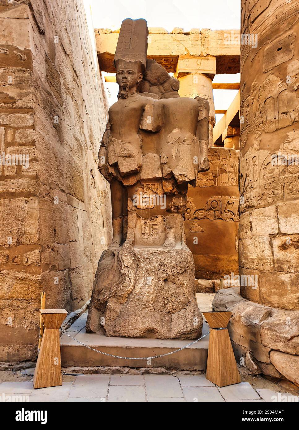 Ruined statue of Ramesses II depicted as the God Amun Ra in the inner precinct at the Karnak ...