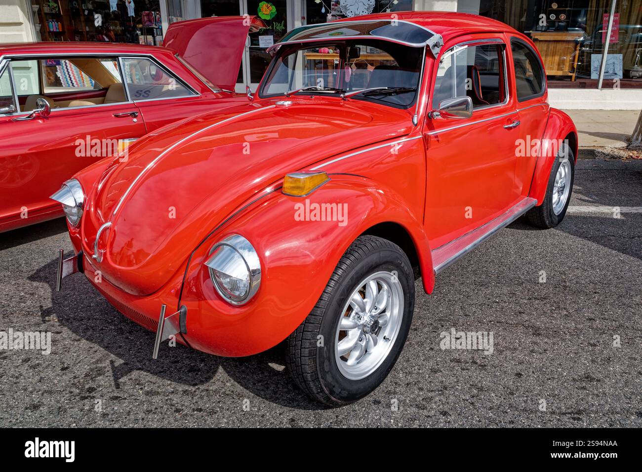 At a car show outdoors is a shiny bright red Volkswagon bug fully ...