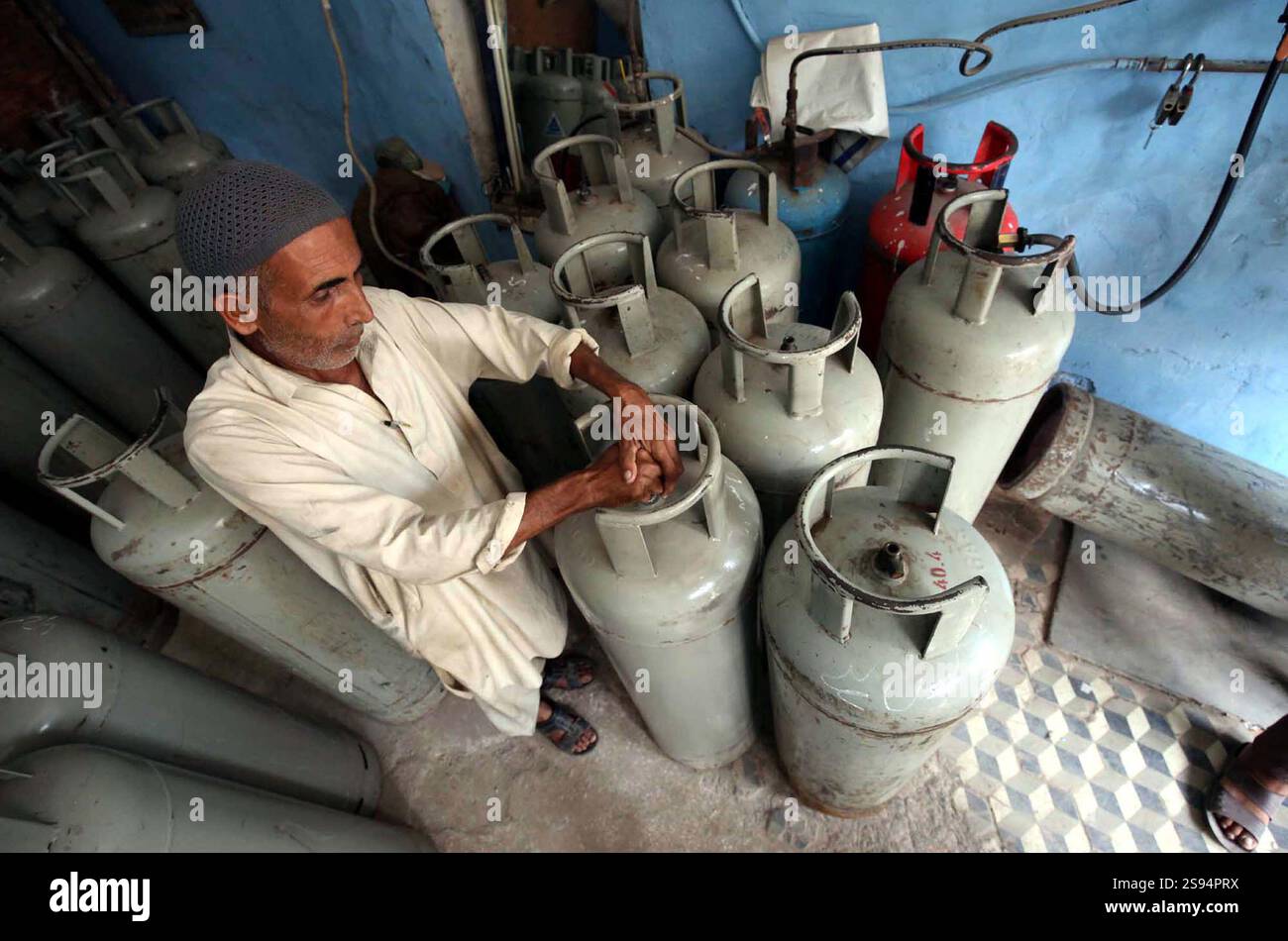 A man filling Liquefied Petroleum Gas (LPG) into cylinder at his shop ...