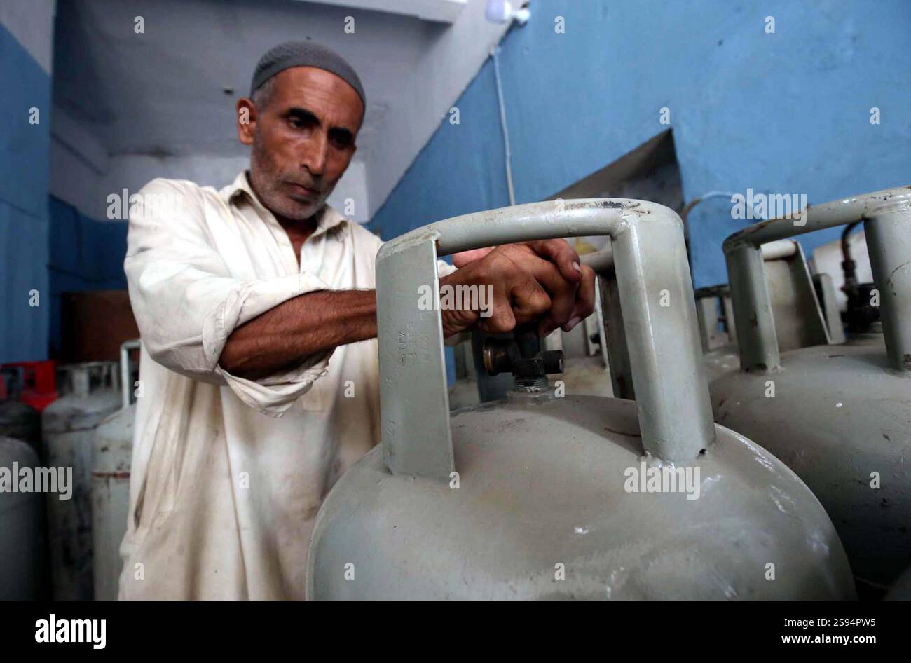 A man filling Liquefied Petroleum Gas (LPG) into cylinder at his shop ...