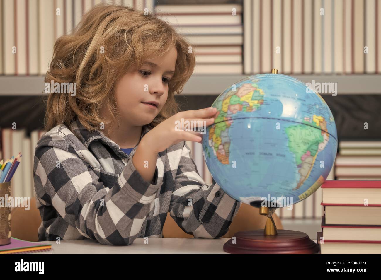 School pupil looking at globe in library, geography lesson. School ...