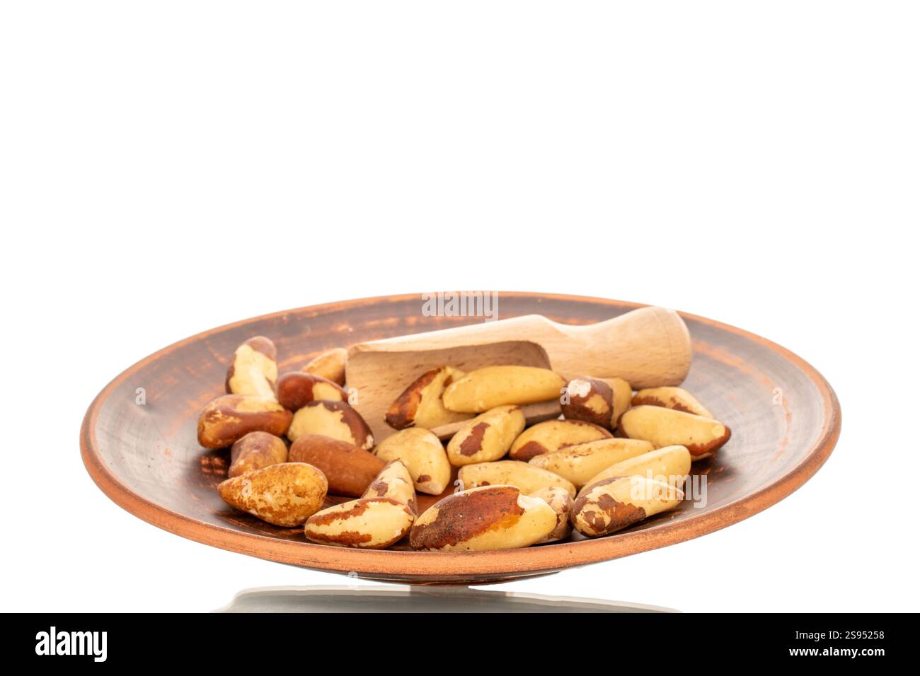 Brazil nuts without shells with clay saucer and wooden spoon, macro ...