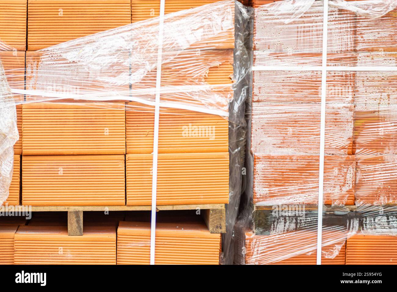 Side view of stacked orange bricks tied with white plastic tape and ...