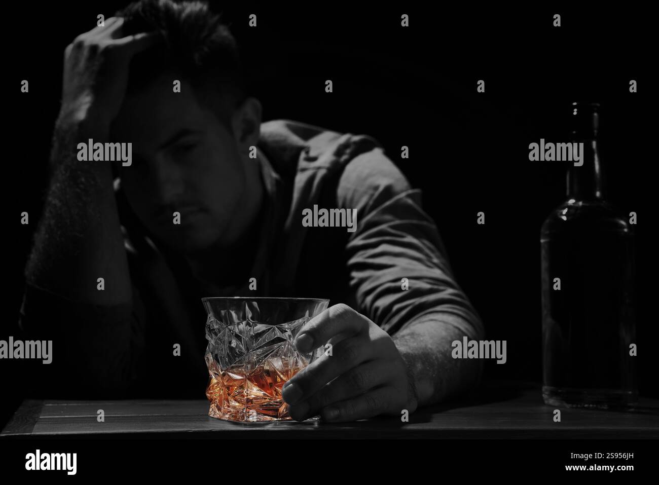 Alcohol addiction. Drunk man with alcohol at table in darkness Stock ...