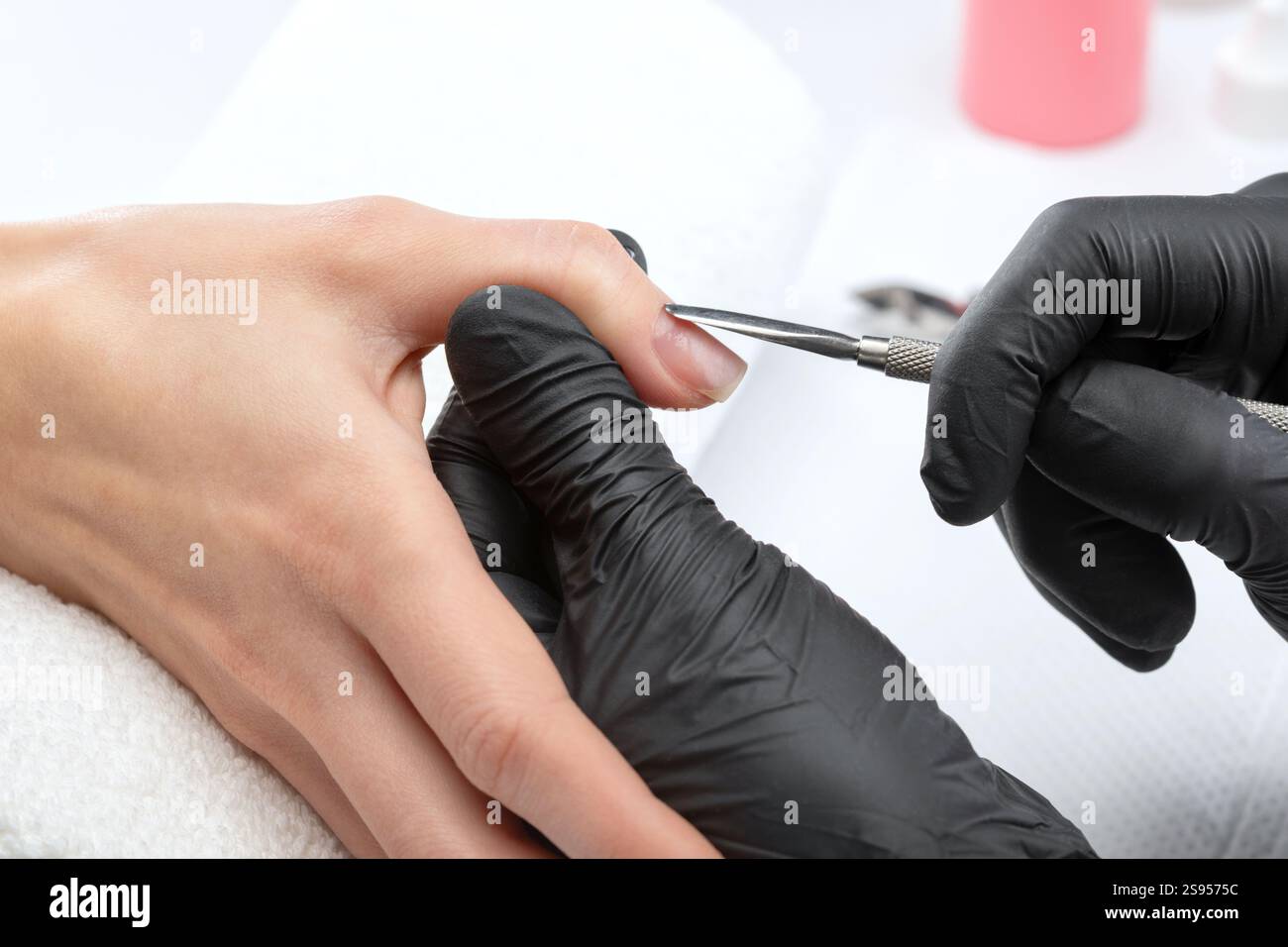 A manicurist removes cuticles during a nail extension procedure in a ...