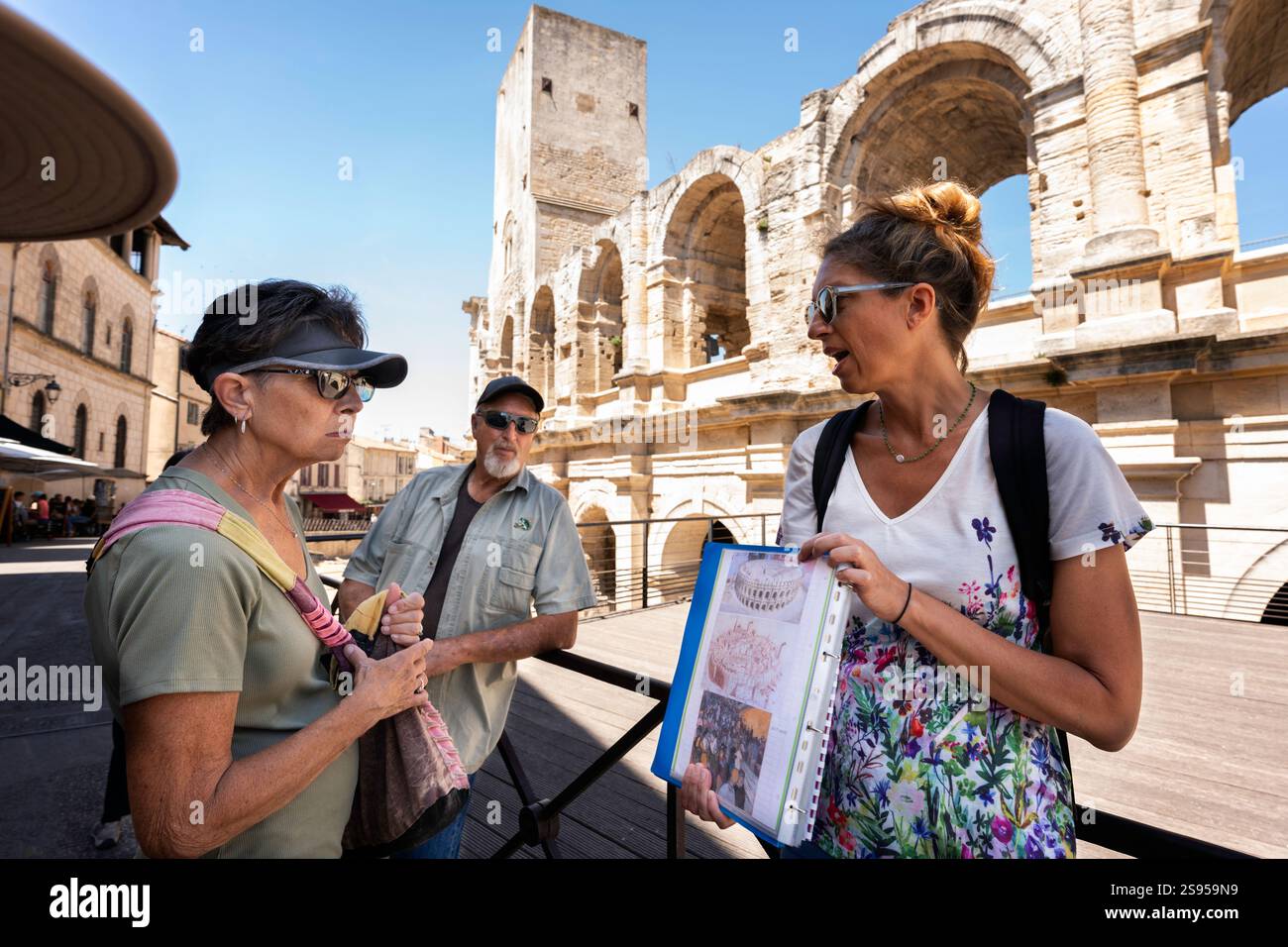 Tour guide shows pictures of the Roman Arena in Arles, Provence, France ...