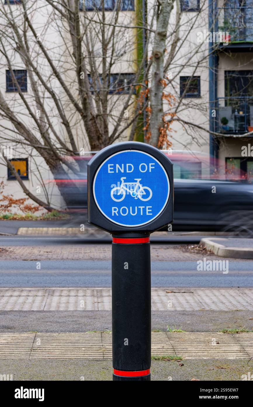 Blue end of route sign for bicycles on a roadside post with blurred car ...