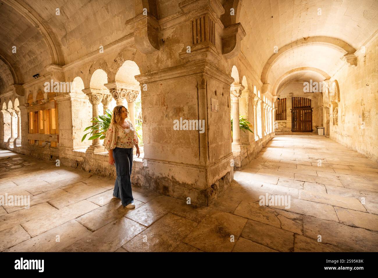 Blond tourist visits the inner courtyard of the peaceful St. Paul de ...