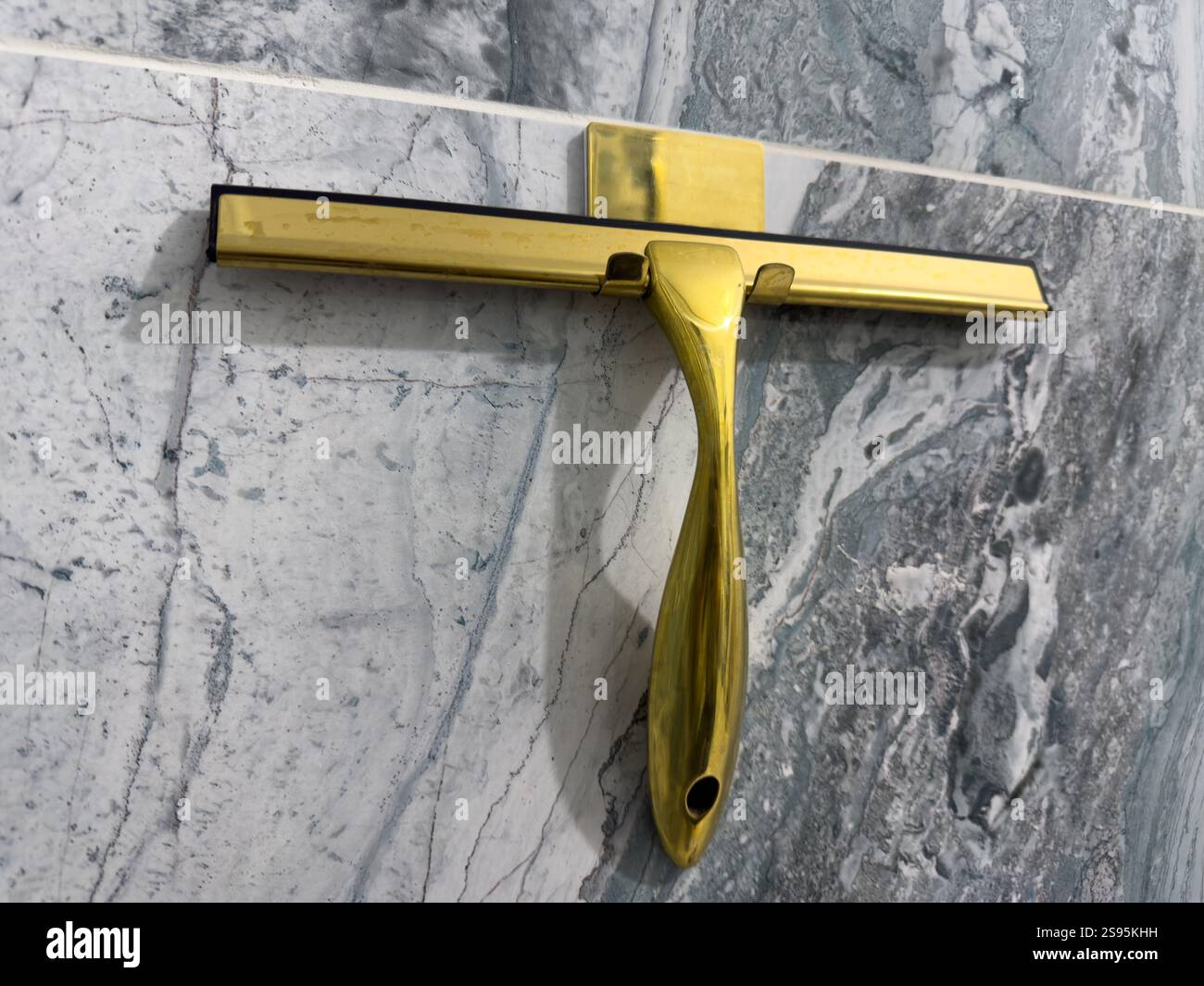Unique gold squeegee displayed on elegant marble wall in a modern ...