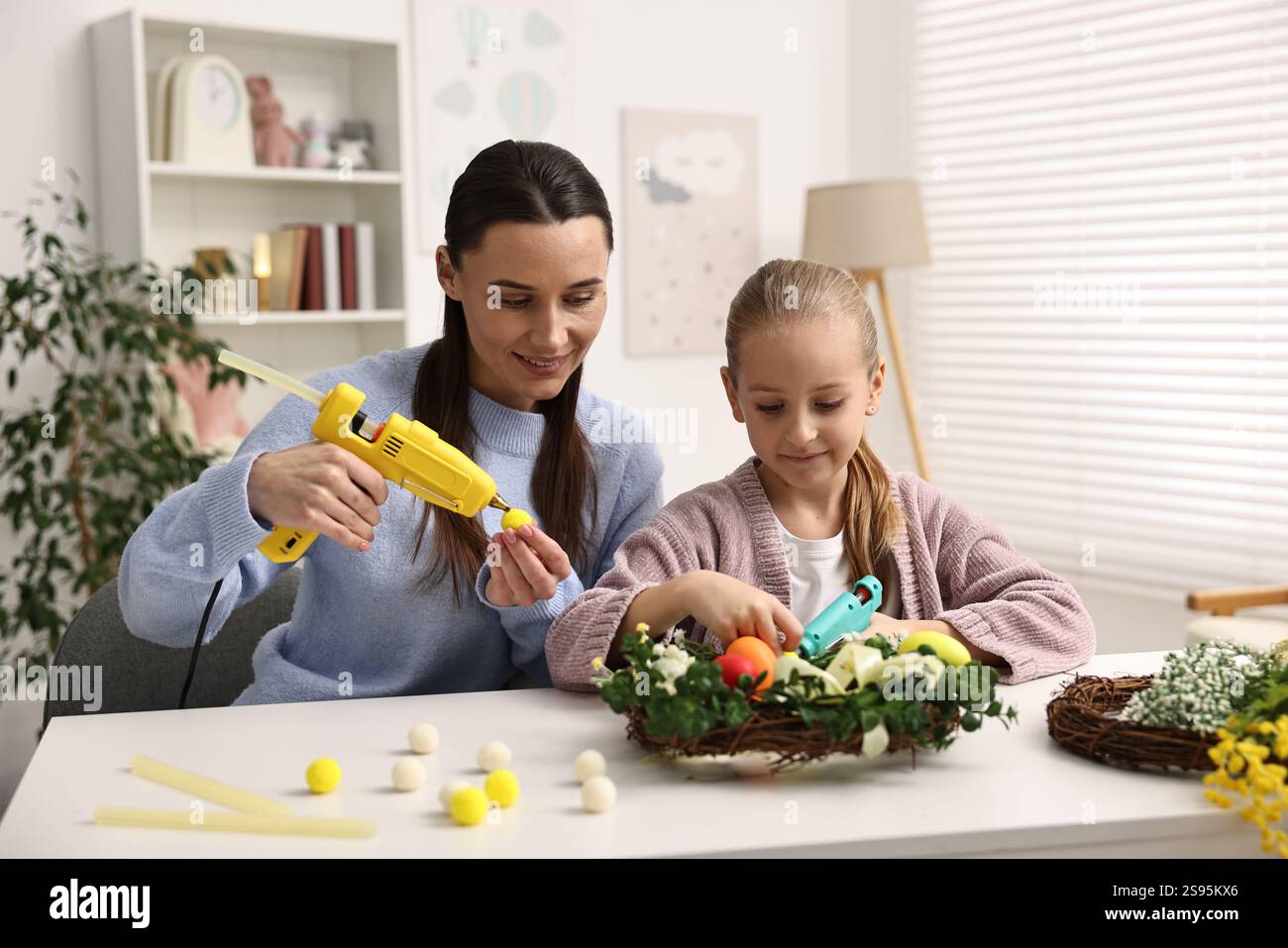 Mother and daughter with hot glue guns creating Easter composition at ...