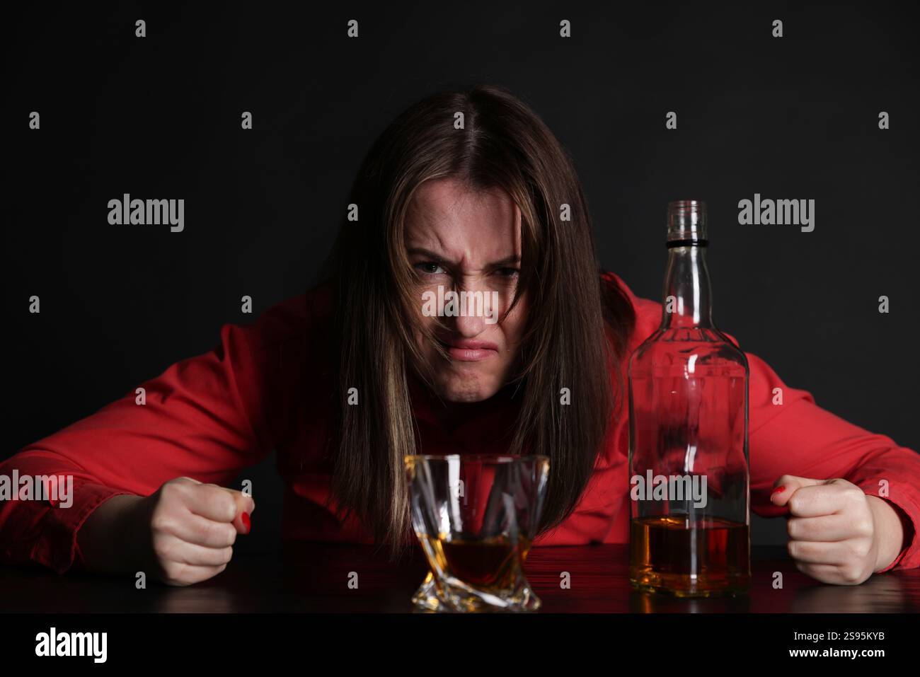 Alcohol addiction. Angry woman with whiskey at table in dark Stock ...