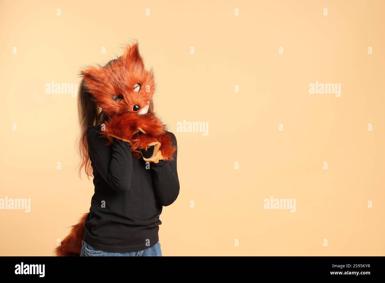 Quadrobics. Girl wearing fox mask, tail and gloves on beige background ...