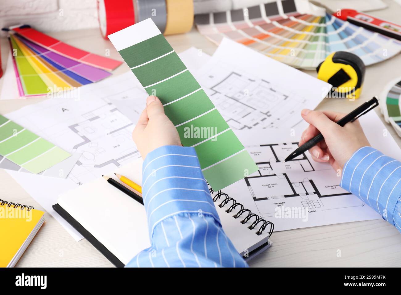 Designer with color selection chart working on house project at table ...