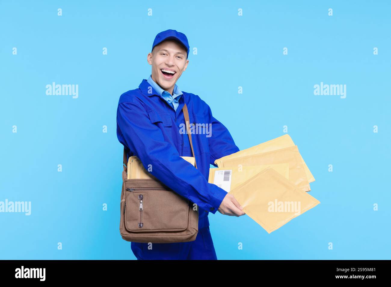 Happy postman with bag and envelopes on light blue background Stock ...