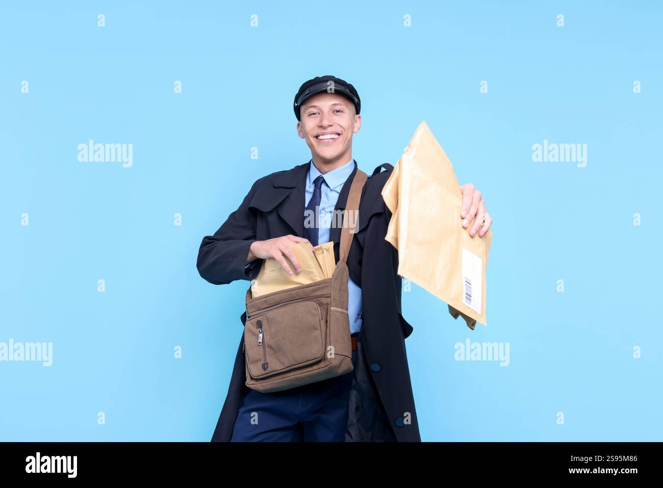 Happy postman with bag giving envelopes on light blue background Stock ...