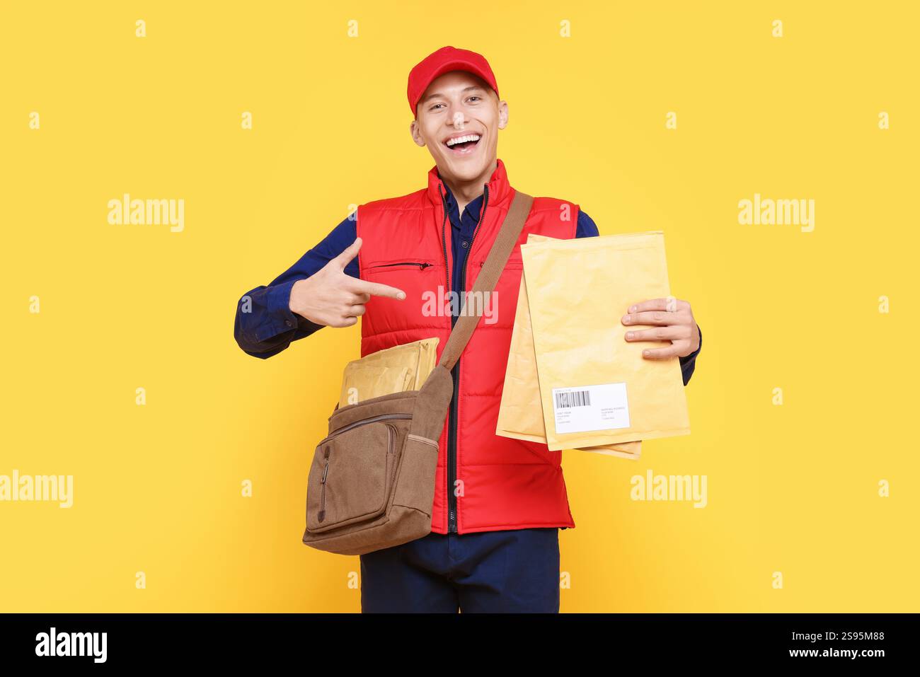 Happy postman with bag pointing at envelopes on yellow background Stock ...