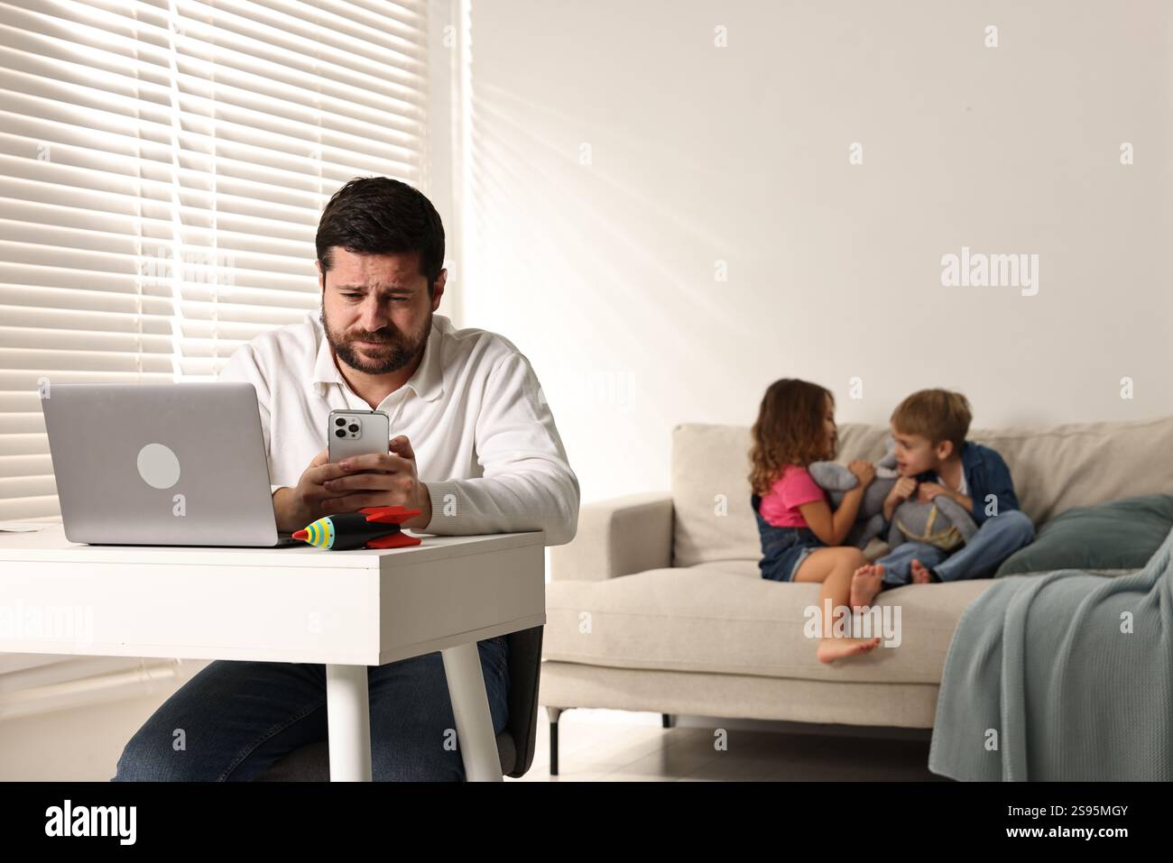 Naughty children disturbing their overwhelmed father at home Stock ...