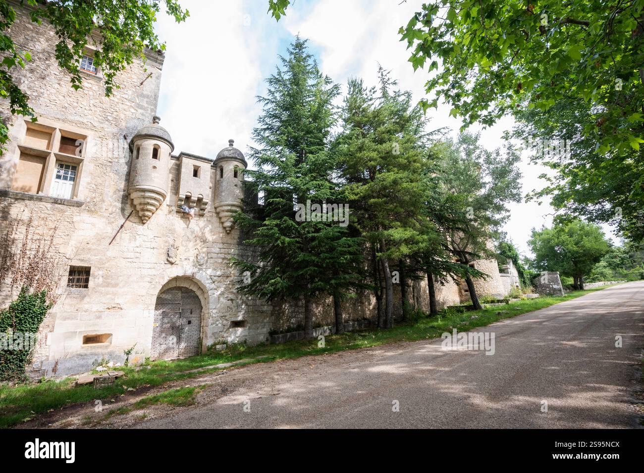 Ancient stone estate with minature turrets along a rural country road ...