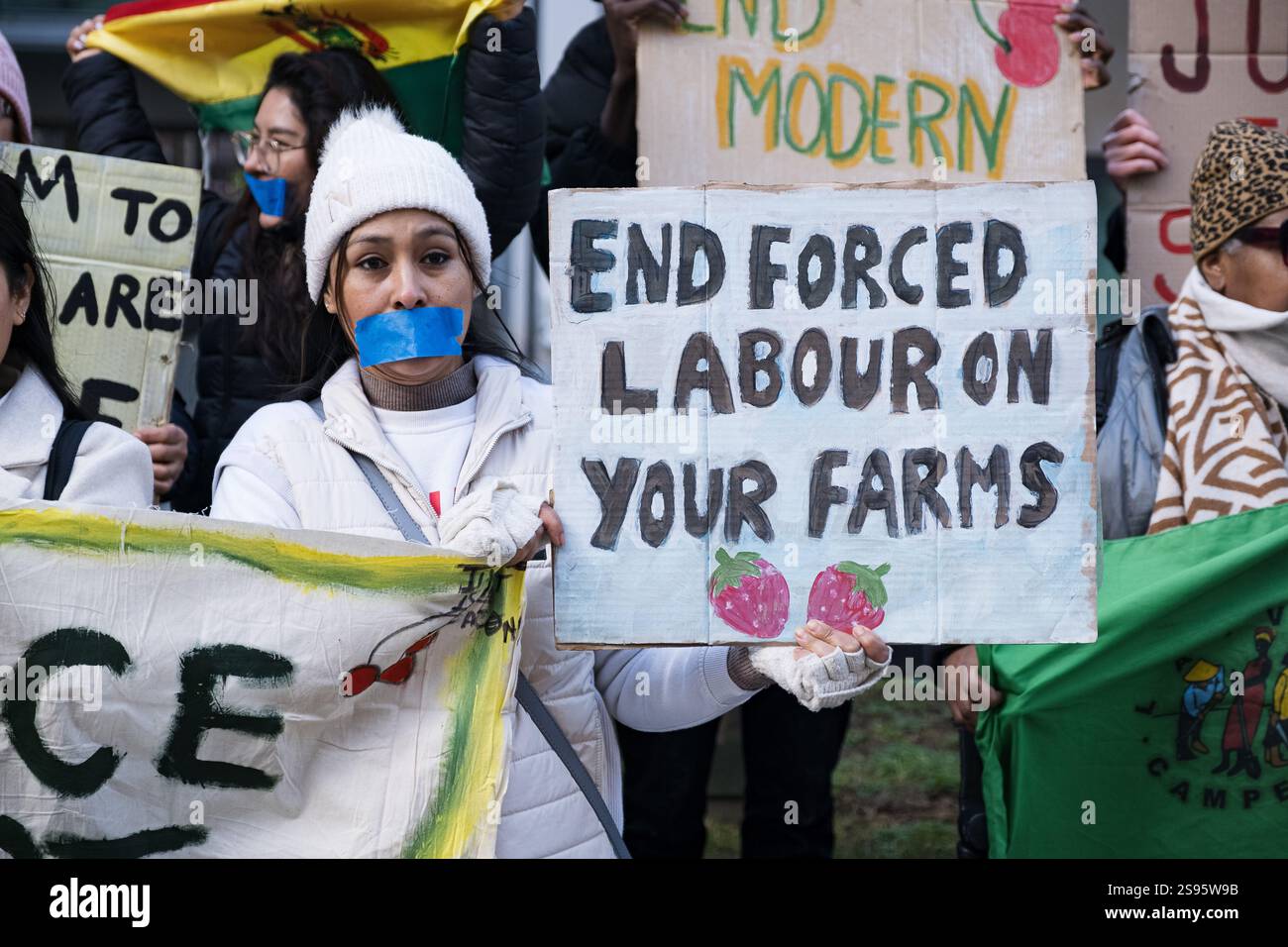A protestor is seen holding a placard that says "End forced labour on ...