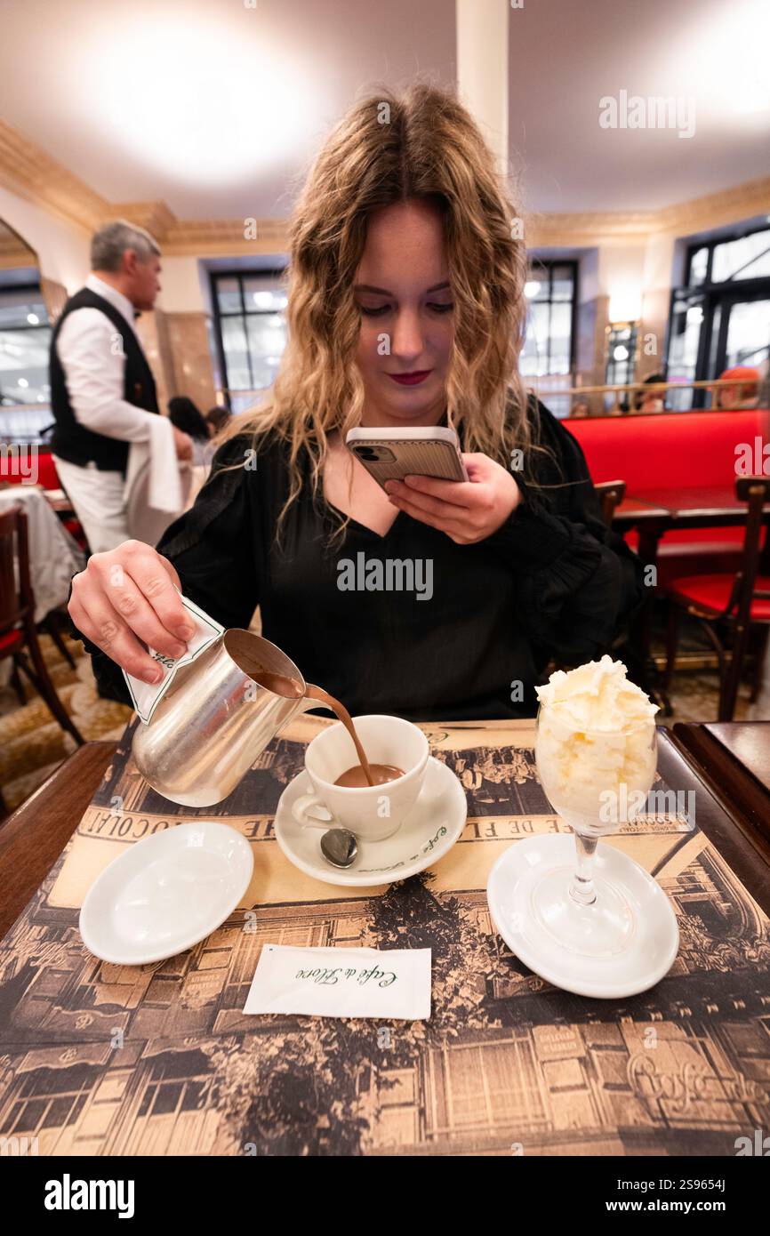 Blond woman enjoys hot chocolate at the historic Cafe Flores restaurant ...