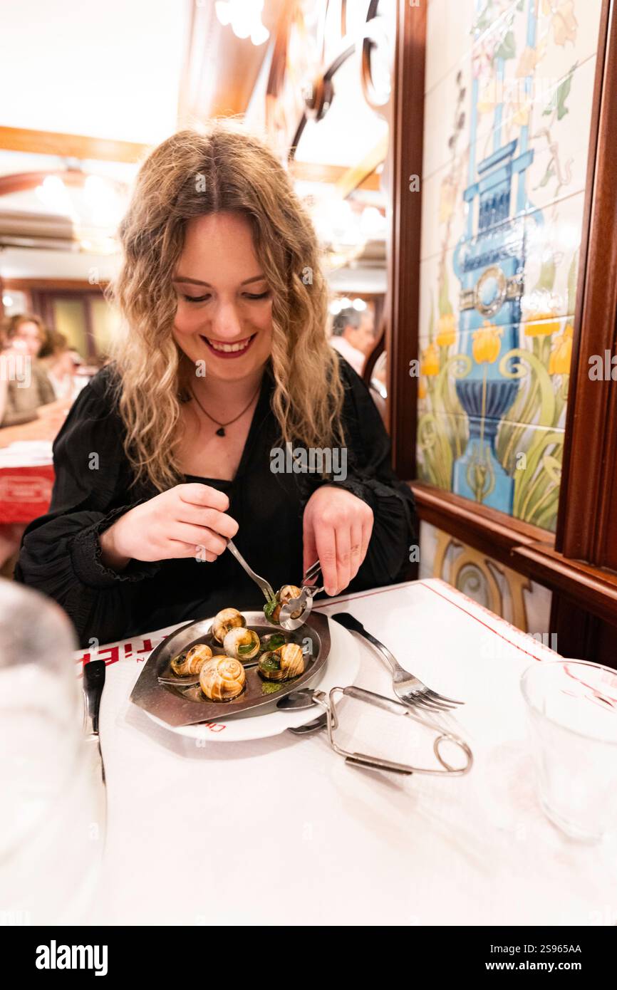 Blond woman eating escargo snails while dining at Bouillon Chartier, an ...