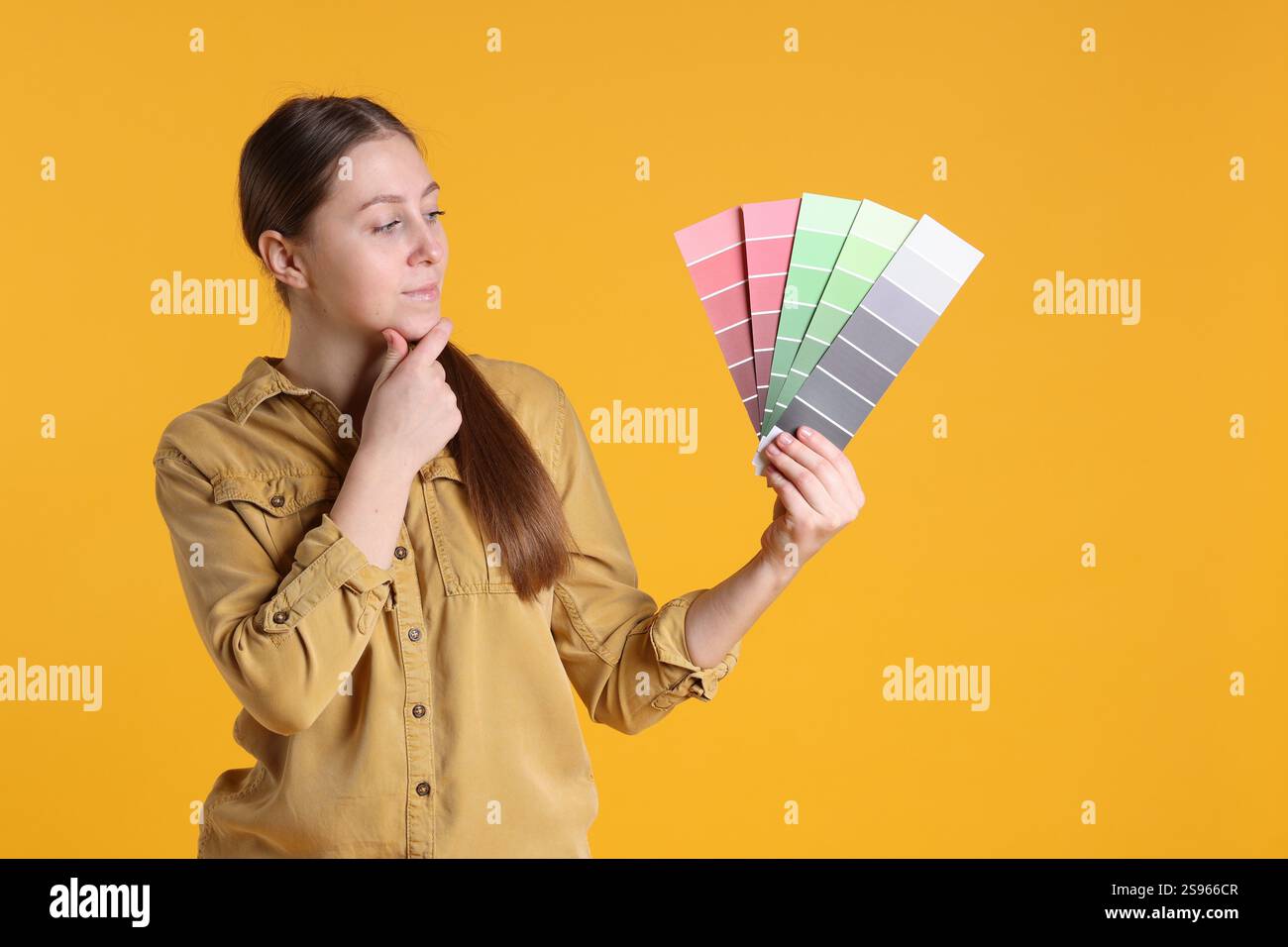 Woman with paint color selection chart on orange background Stock Photo ...