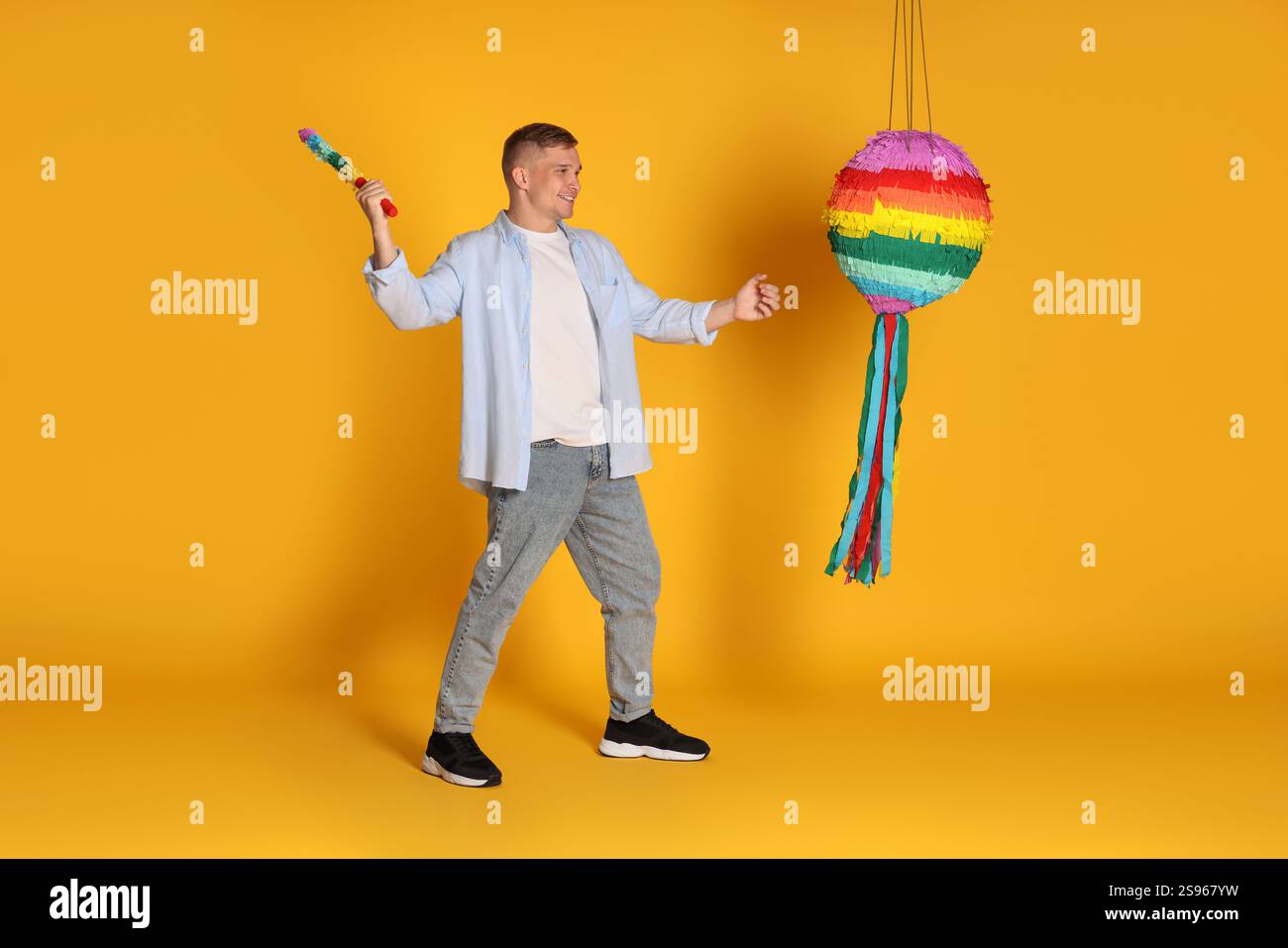 Happy man breaking pinata on yellow background Stock Photo - Alamy