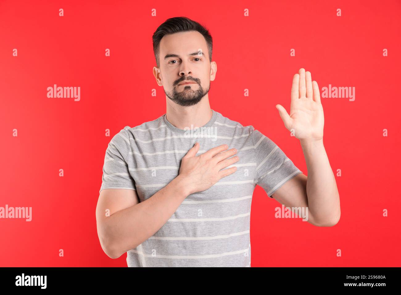 Man making promise with raised hand on red background. Oath gesture ...