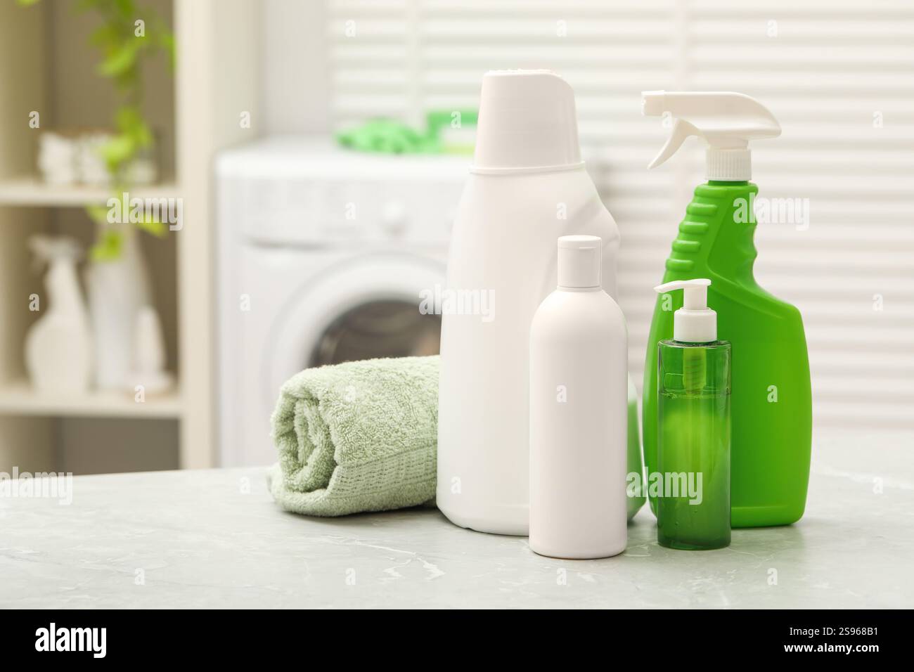 Different laundry detergents and rolled towel on light table in ...